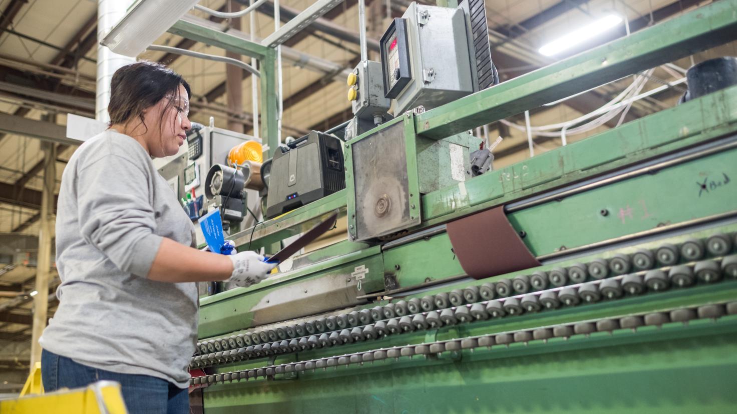 Woman using a large assembly line machine.